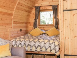 Um quarto de cabana aconchegante com uma cama, um sofá e uma janela com cortinas.