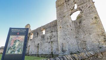 Ruínas do Castelo de Middleham com uma placa de identificação.