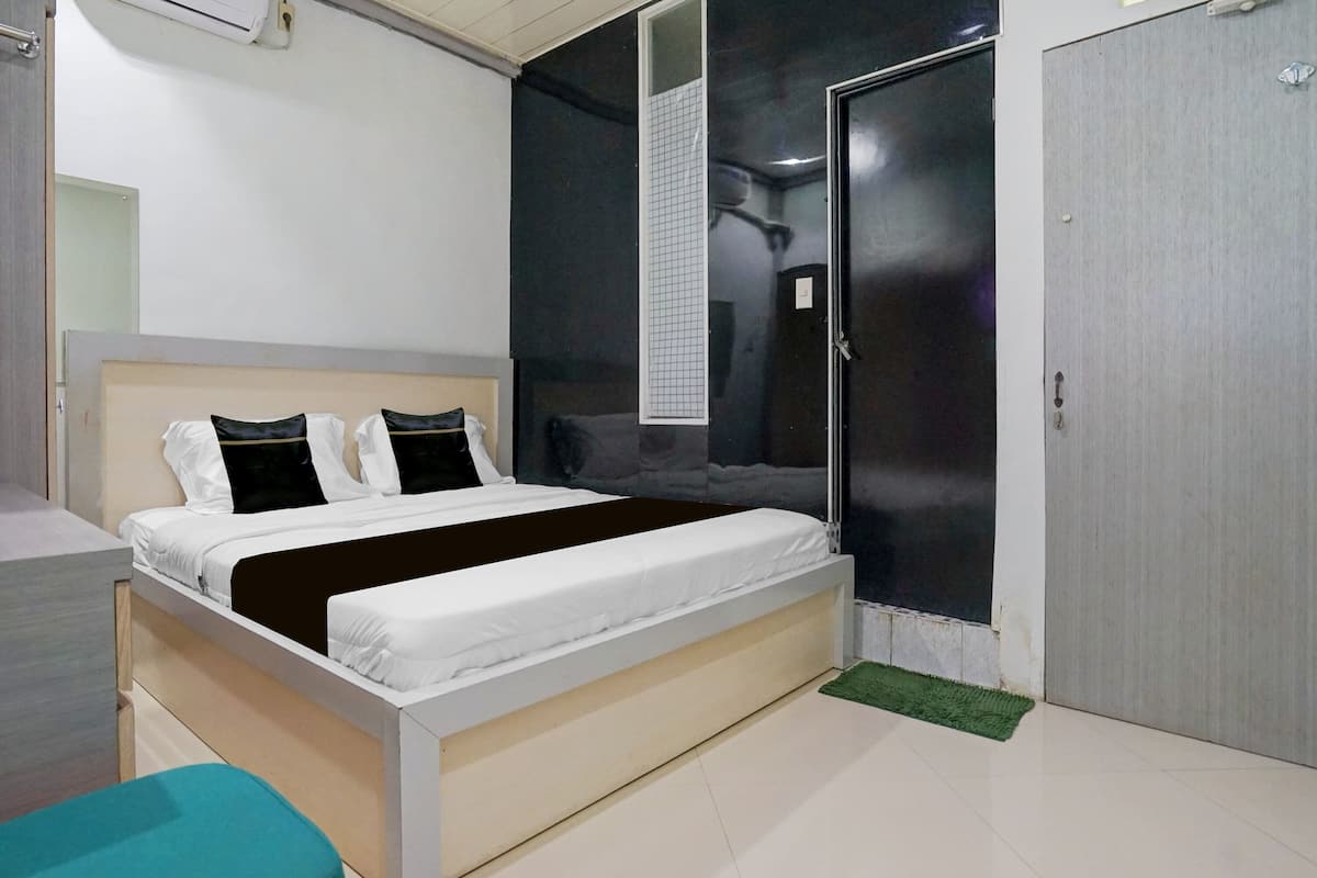 Quarto moderno com cama, guarda-roupa e um pequeno espaço de estar.