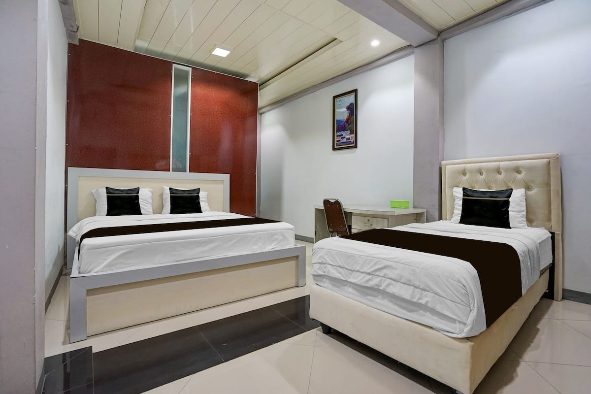Quarto de hotel com duas camas, uma mesa e uma cadeira.