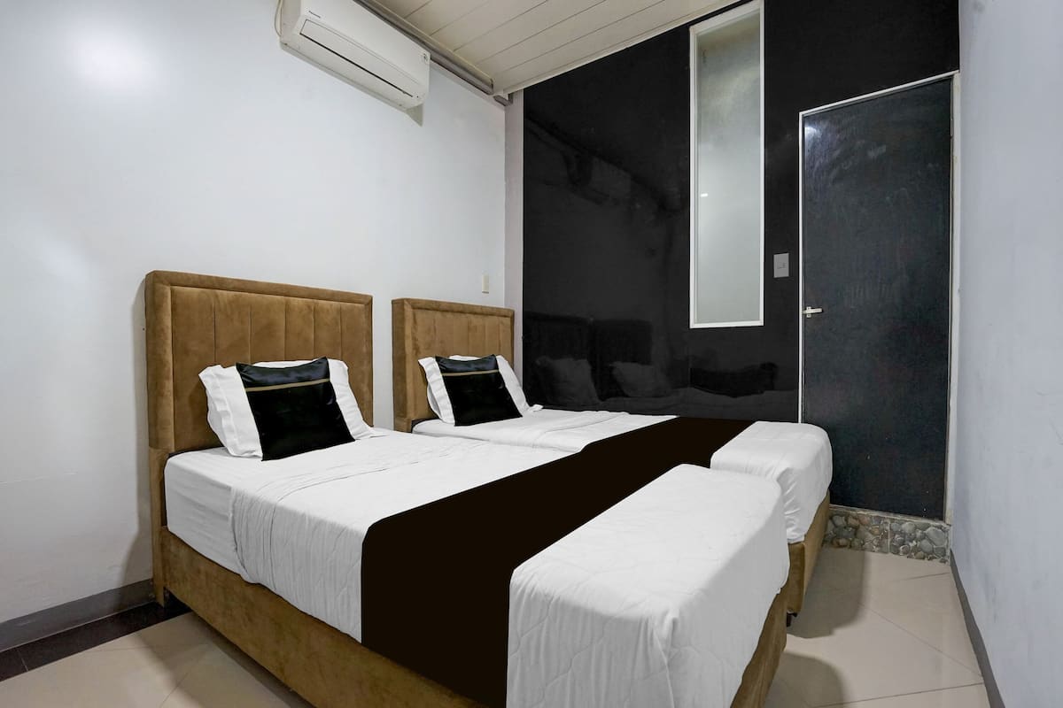 Uma cama de casal com cabeceira de madeira, mesa de cabeceira, um espelho e uma porta com moldura escura.