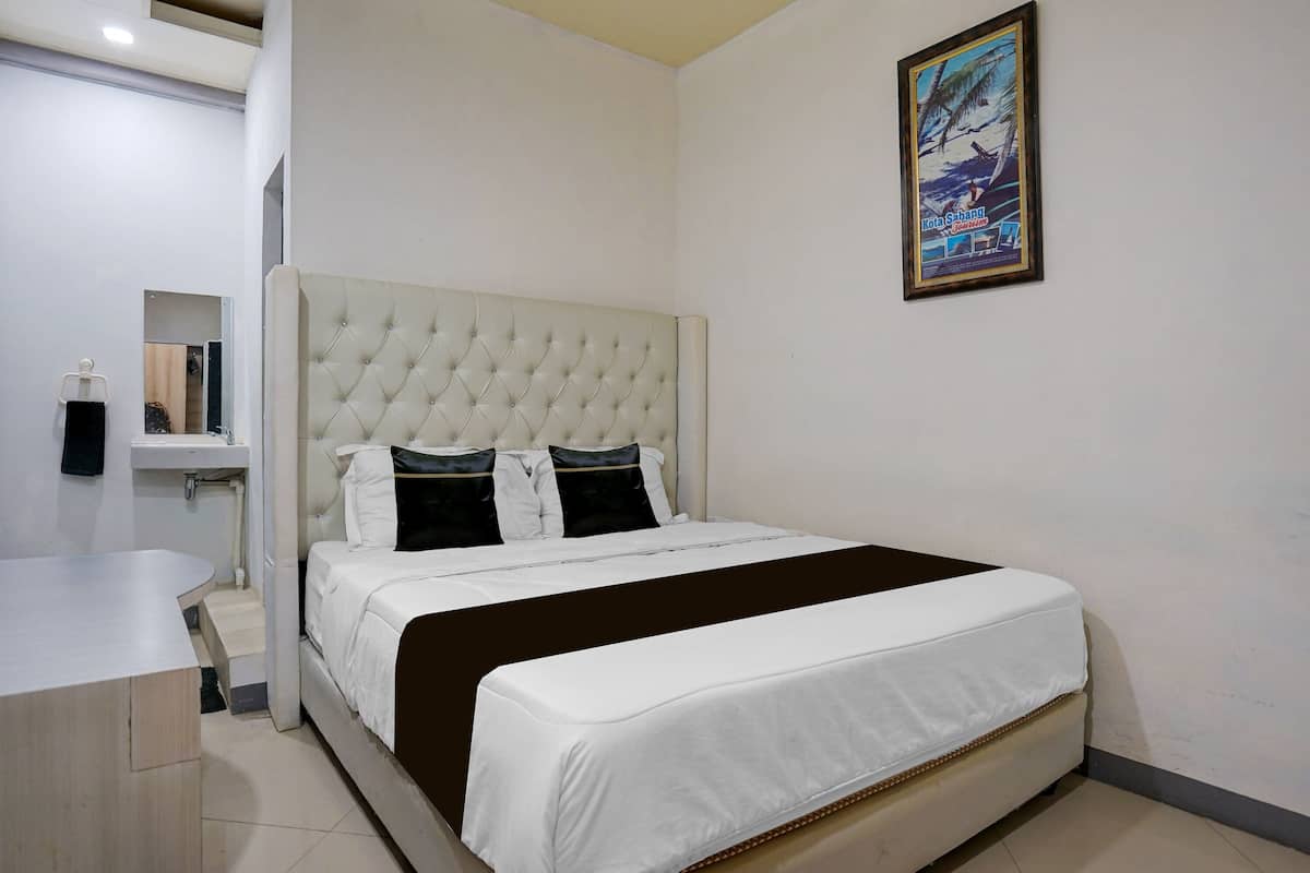 Quarto bem arrumado com uma cama grande, uma mesinha de cabeceira e um quadro pendurado na parede.