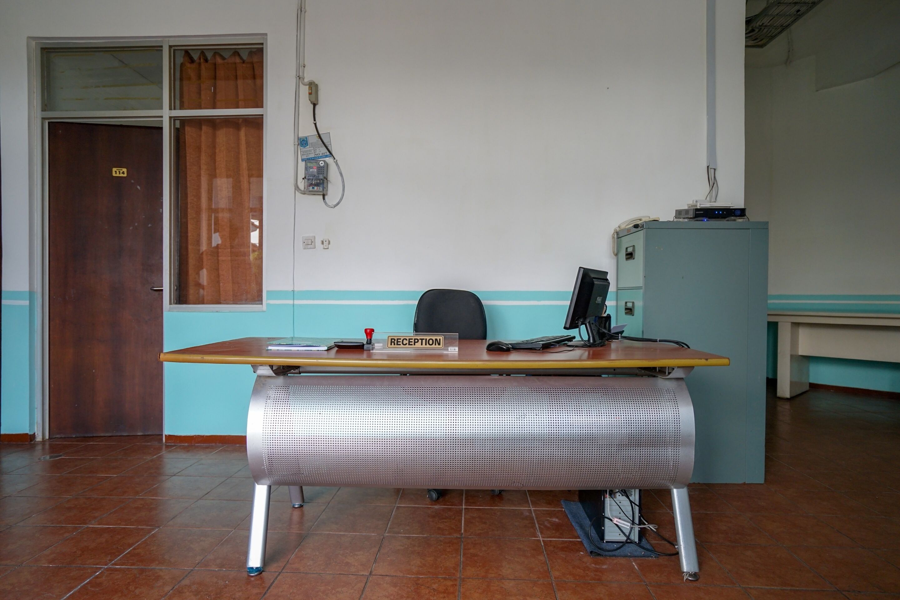 Uma mesa de recepção com uma placa de identificação, um computador e um telefone.