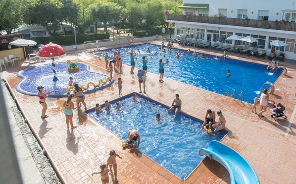 Uma área de piscina com várias piscinas, toboáguas e espreguiçadeiras.