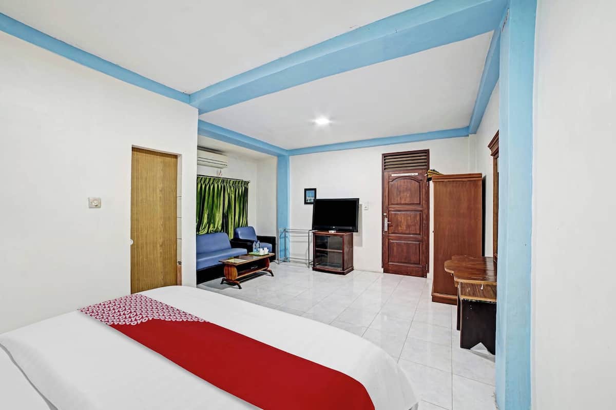 Quarto de hotel com cama, sofá, televisão e armário de madeira.
