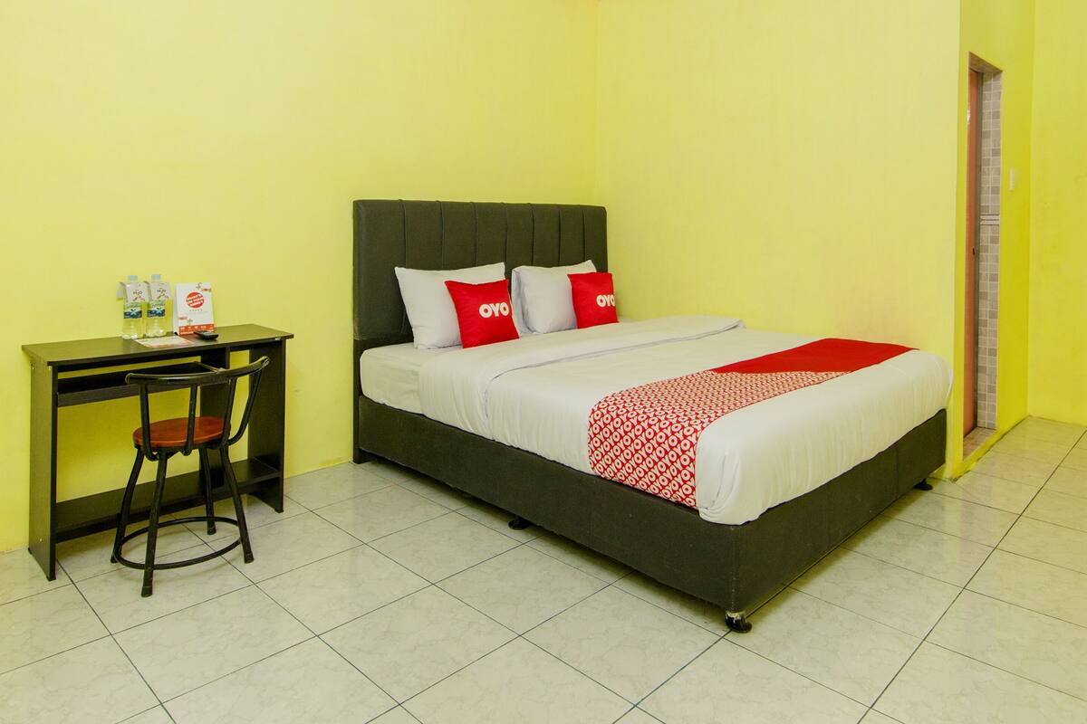 Quarto de hotel com uma cama, uma escrivaninha e uma cadeira.