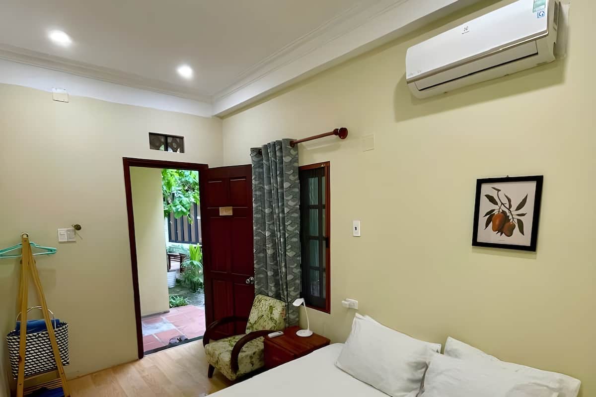 Quarto com cama, escrivaninha, cadeira, ar-condicionado e porta para área externa.