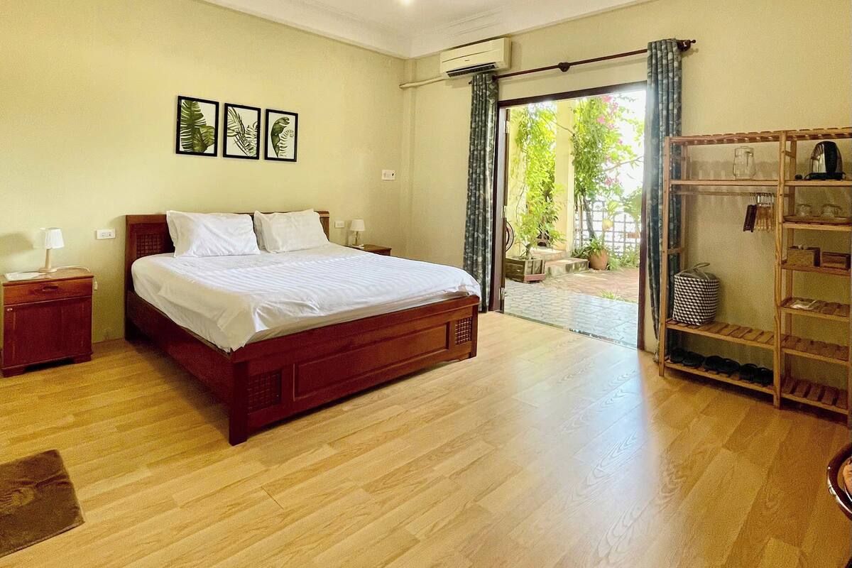 Quarto com cama de madeira, mesa de cabeceira e sapateira.