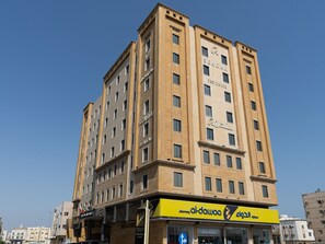 Um edifício alto com várias janelas e uma placa amarela de farmácia.