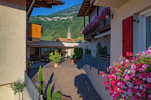 Pátio com área de estar ao ar livre, vista para as montanhas e um edifício com uma persiana vermelha.