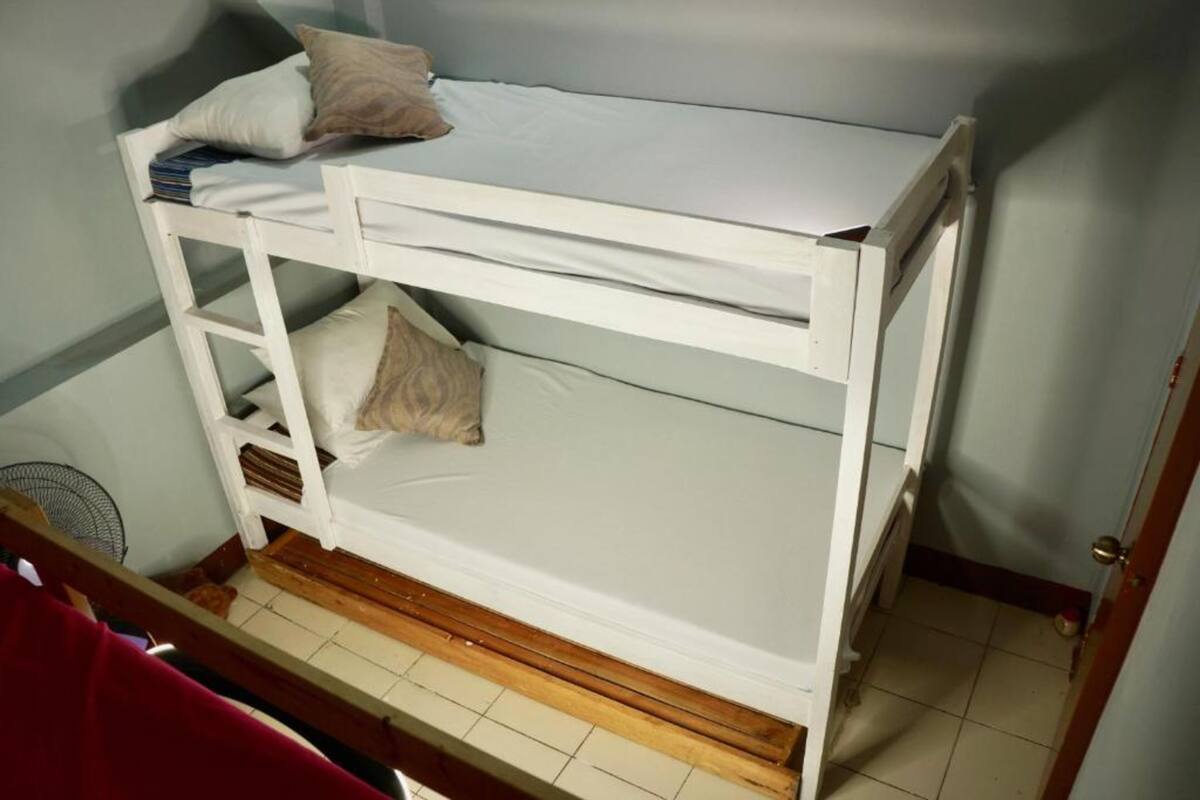 Uma cama de solteiro com estrutura de madeira e roupa de cama branca.