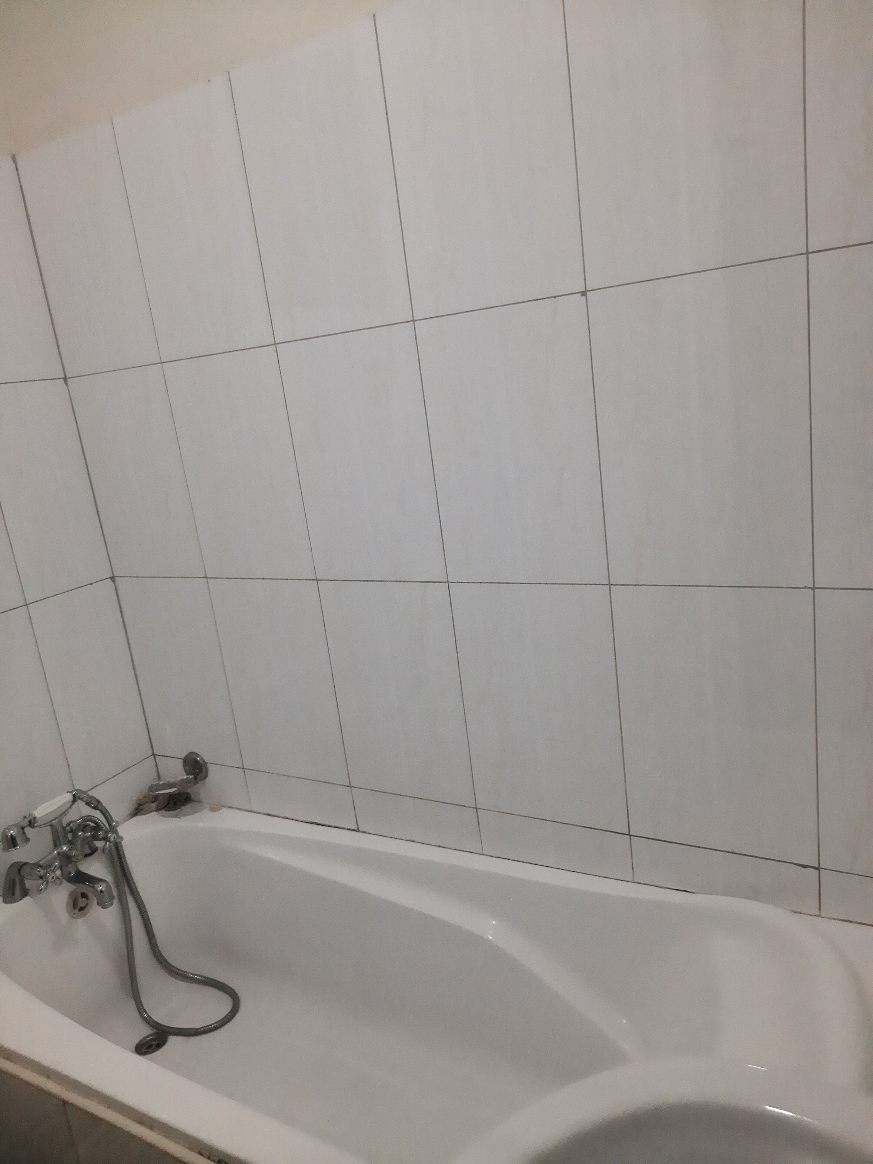 Casa de banho com paredes revestidas a azulejos brancos e uma banheira.