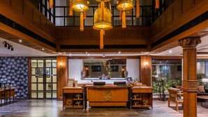 Um hall amplo com uma recepção central, lanternas penduradas e um teto alto.