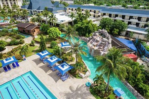 Um resort com piscina, tobogã e um edifício grande ao fundo.