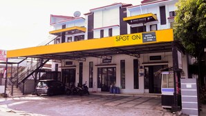 Um hotel com toldo amarelo, escadaria que leva à entrada e placa indicando o nome e endereço do hotel.