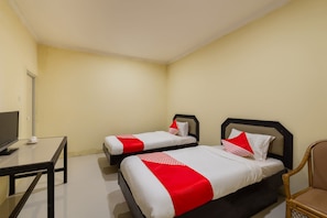 Quarto de hotel com duas camas, uma escrivaninha, uma cadeira e uma televisão.