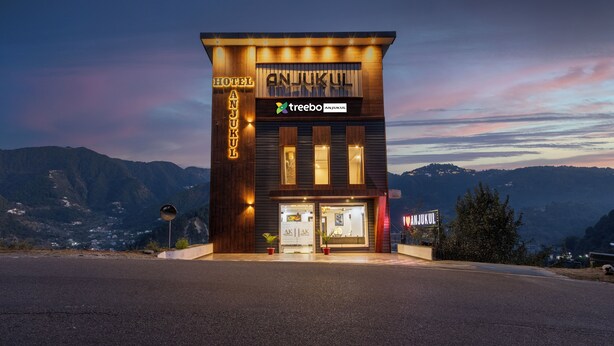 A modern hotel with a prominent sign reading "ANJUKUL HOTEL" and "treebo ANJUKUL" on the facade.
