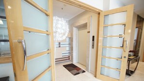 Um corredor com portas de vidro fosco, teto branco e luminária moderna.