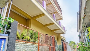 Edifício residencial com varanda, portão fechado e uma motocicleta estacionada em frente.