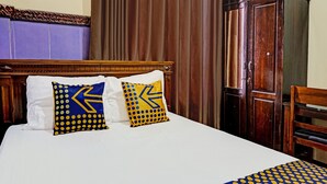 Cama bem arrumada com lençóis brancos e dois travesseiros decorativos com padrões geométricos.