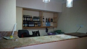 Uma área de cozinha com bancada, uma prateleira com diversos frascos e uma cadeira.