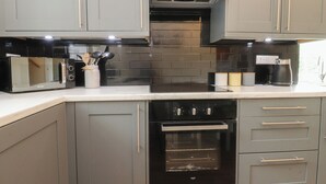 Uma cozinha moderna com armários cinza, forno embutido e micro-ondas.