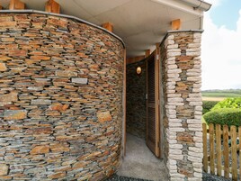 Mural de pedra com porta e cerca de madeira.
