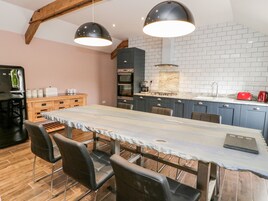 Uma cozinha moderna com bancada de mármore, cadeiras de madeira e uma mesa de jantar grande.