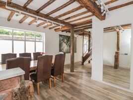 Uma sala de jantar ampla, com teto de madeira e grandes janelas.