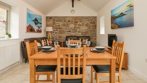 Uma sala de jantar com parede de pedra, mesa de madeira e cadeiras.