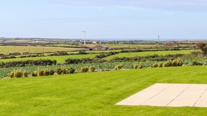 Paisagem rural com turbinas eólicas, campos verdes e céu claro.