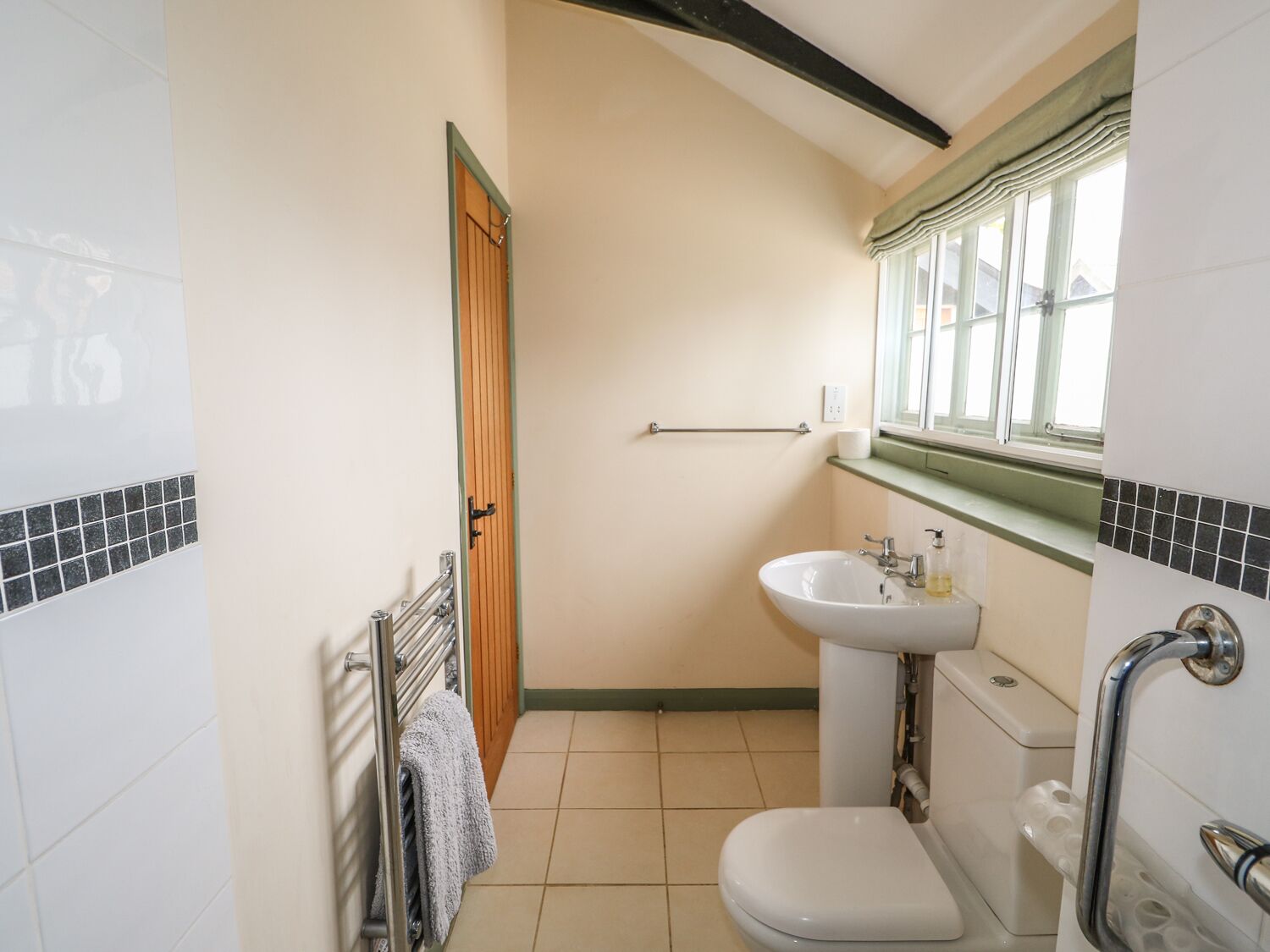 Casa de banho compacta com sanita, lavatório e suporte para toalhas.