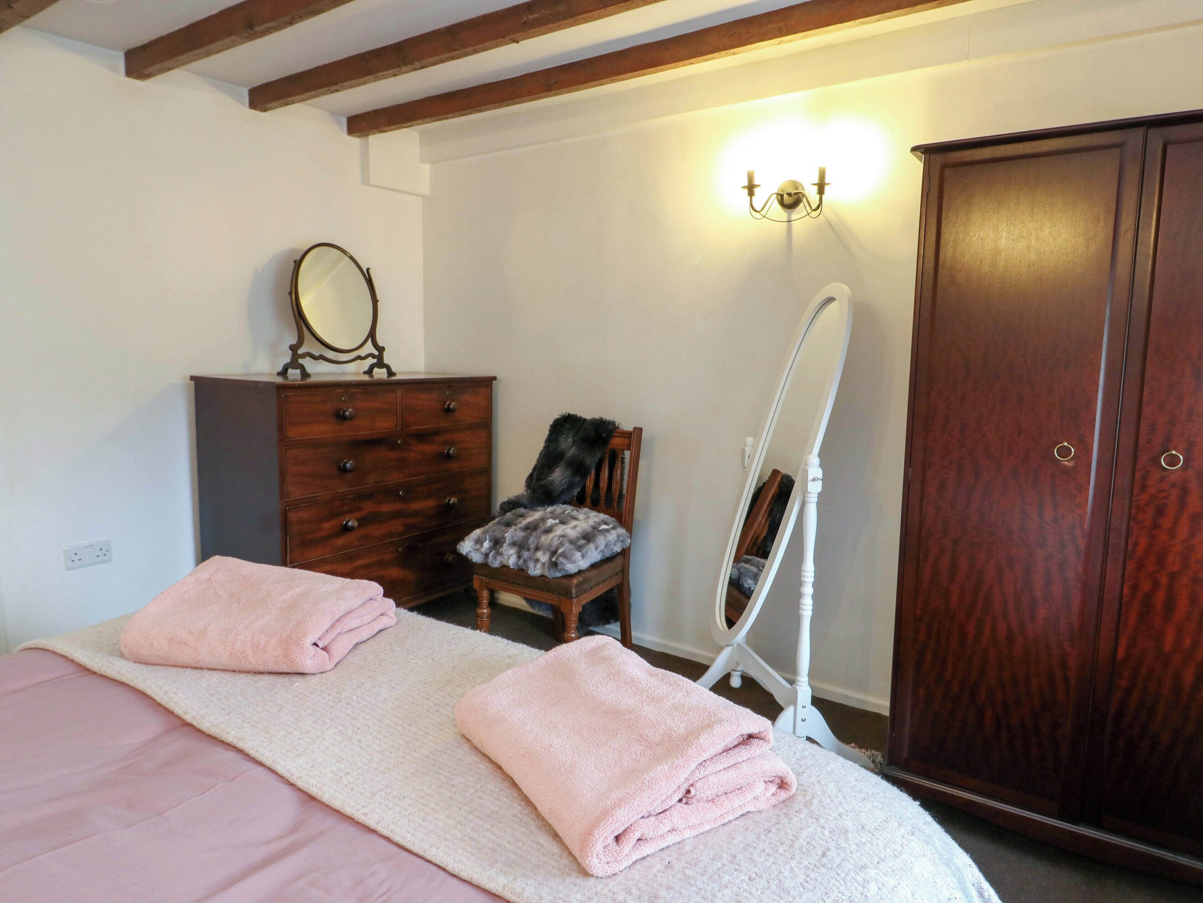 Quarto com cama, penteadeira, cadeira, espelho e guarda-roupa.