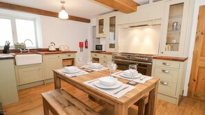 Cozinha moderna com piso de madeira, mesa de jantar posta para seis pessoas e eletrodomésticos embutidos.