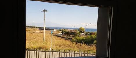 Vista pela janela de uma paisagem com montanha, estrada e cerca.
