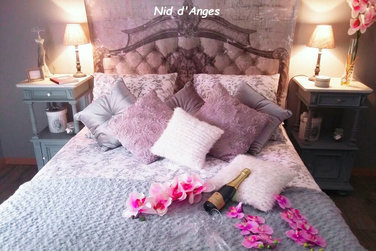 Uma cama com roupa de cama floral, uma garrafa de champanhe e flores cor-de-rosa.