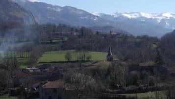 Uma aldeia montanhosa com casas e uma igreja, rodeada por picos nevados.