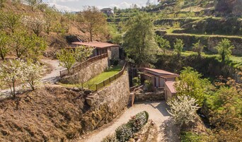 Edifício de paredes de pedra com um jardim em terraços e uma escadaria que leva a um deck de madeira.