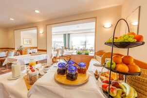 Buffet de café da manhã com diversas opções de comida e uma exposição de frutas.