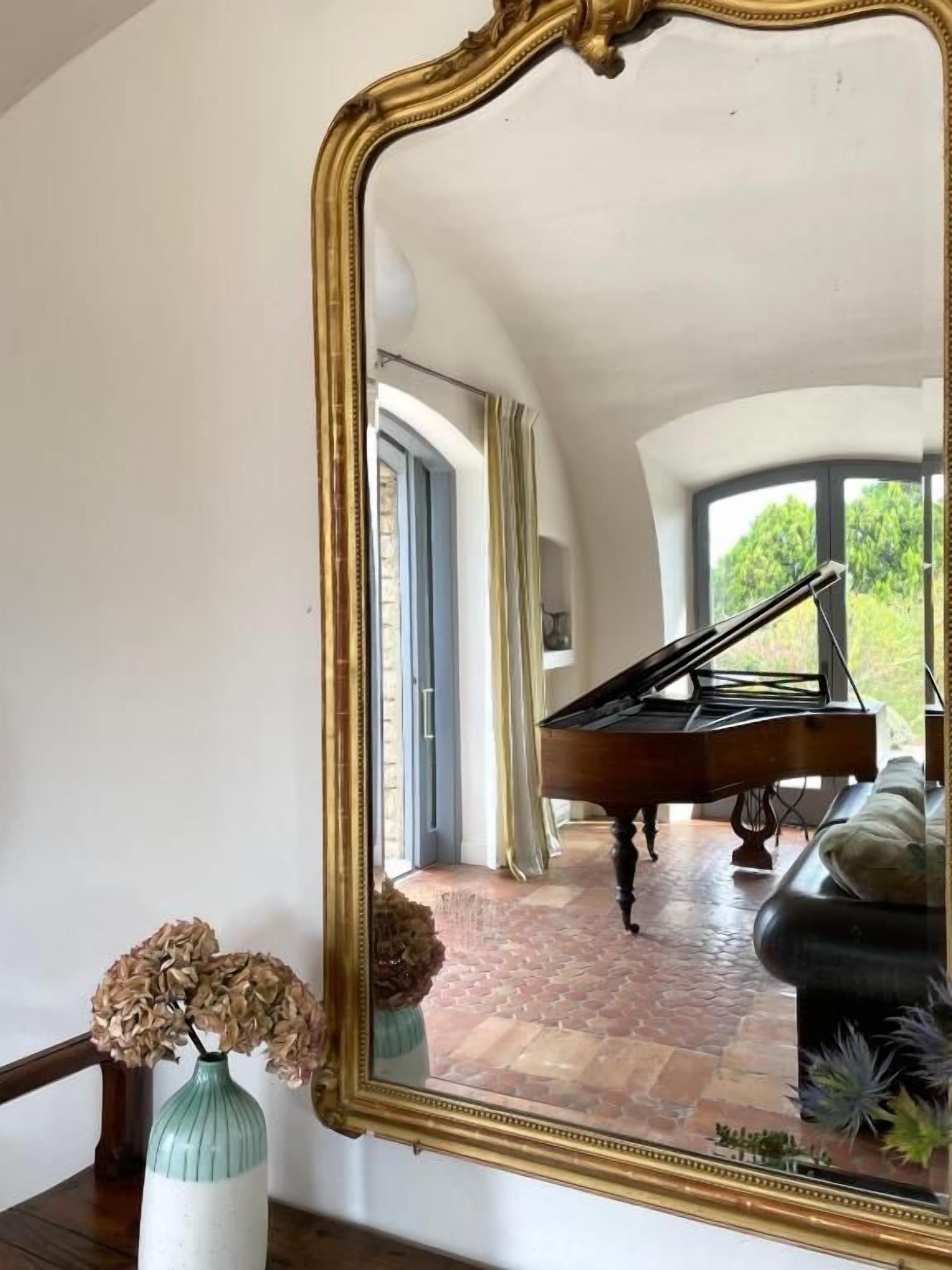 Um piano de cauda em uma sala ampla, com um espelho grande refletindo o interior.