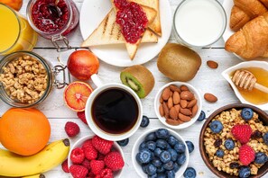 Uma mesa de café da manhã com torradas, frutas, cereais e bebidas.
