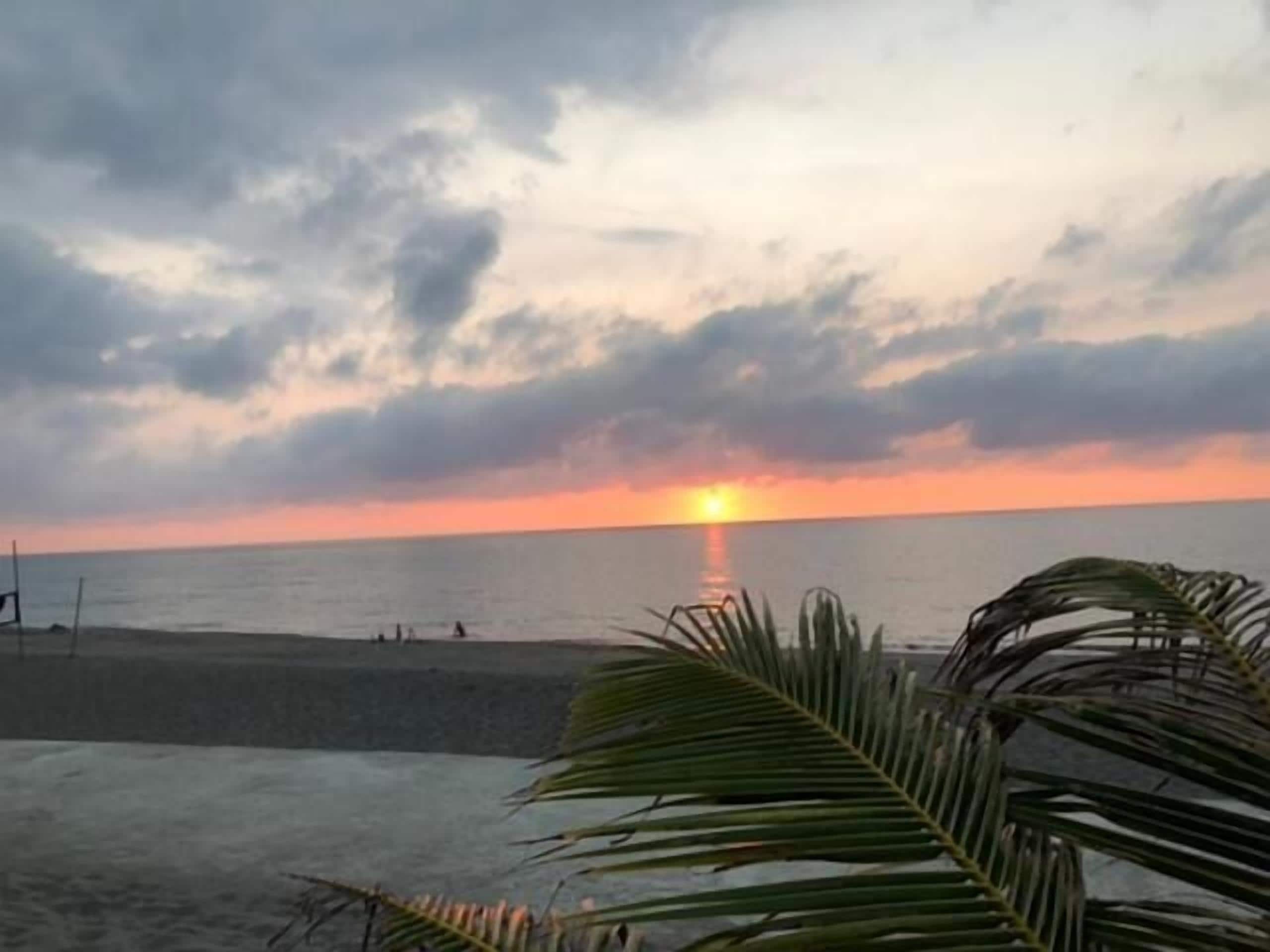 Uma praia com um pôr do sol sobre o oceano.