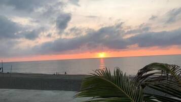 Uma praia com um pôr do sol sobre o oceano.