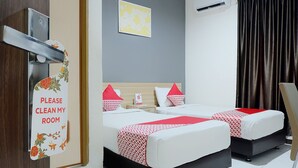 Quarto de hotel com duas camas, um aviso de 'Limpar meu quarto', um ar condicionado fixado na parede e um quadro emoldurado.