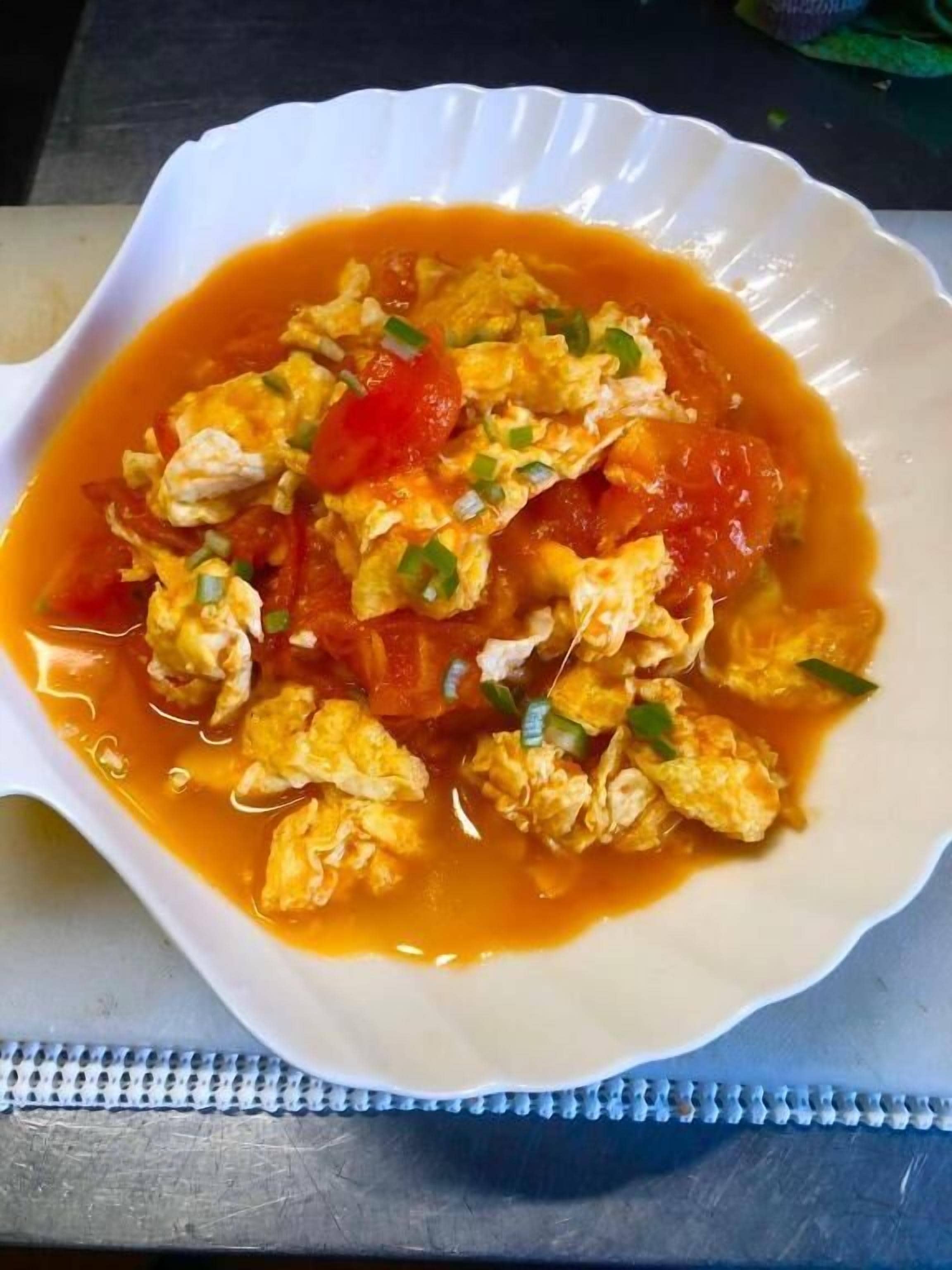 Uma tigela de ovos mexidos com tomate e cebolinha.