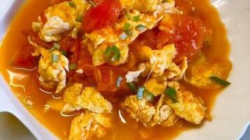 Uma tigela de ovos mexidos com tomate e cebolinha.