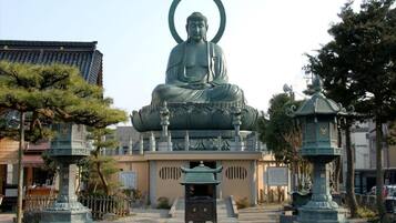 Uma grande estátua de Buda em um pátio cercado por arquitetura japonesa tradicional.