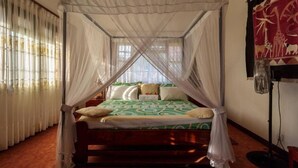Um quarto com cama sob um dossel, janela com cortinas e parede com tapeçaria.