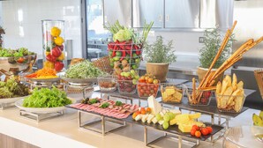 Buffet com diversos alimentos, incluindo saladas, frutas, queijos e carnes.