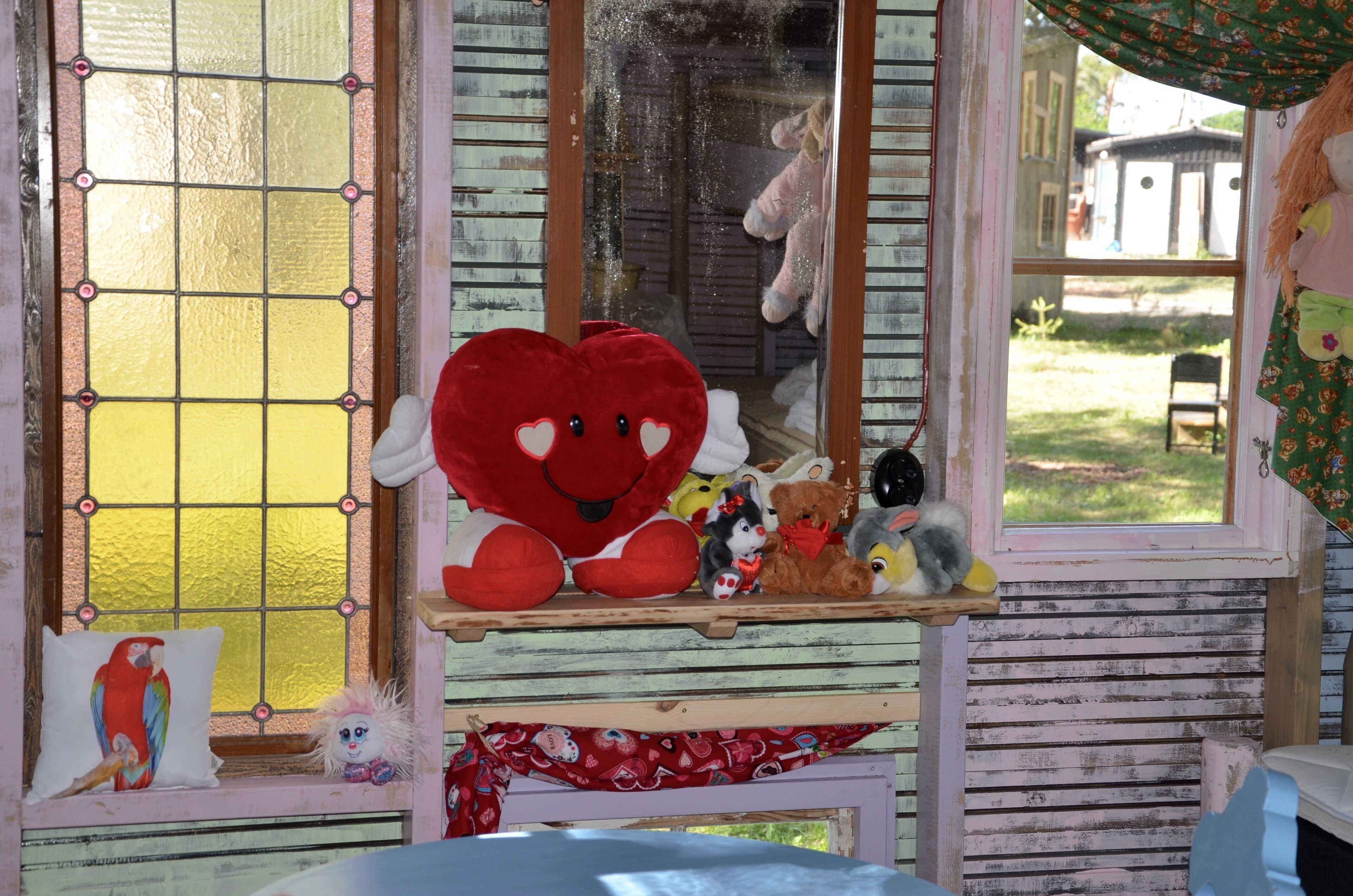 Um quarto aconchegante com uma janela, uma prateleira com brinquedos macios e um travesseiro de papagaio.